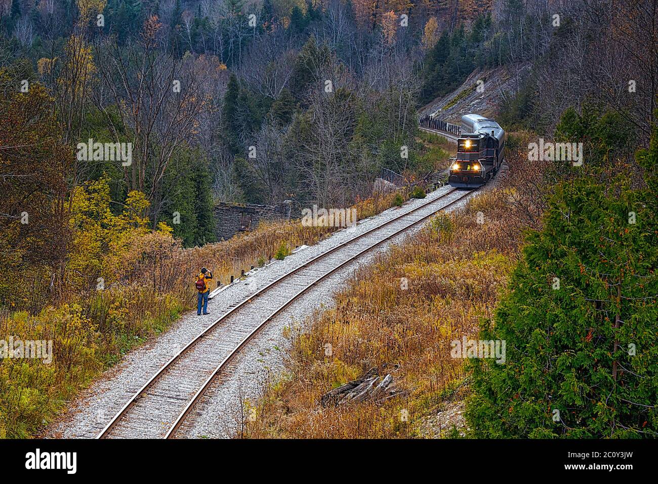 Aerial view of a train on a railroad track with a photographer taking ...