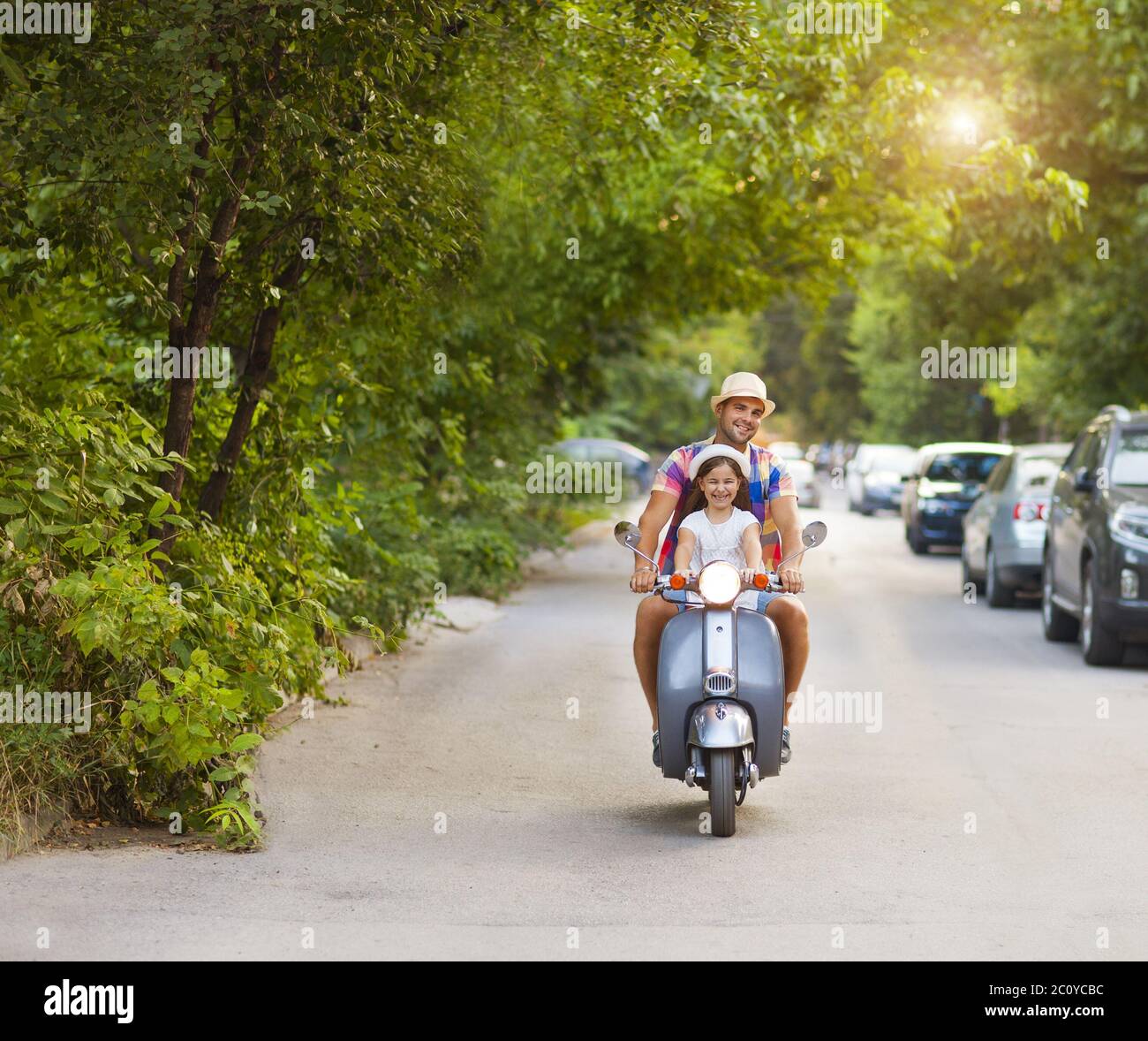 Happy young father and little daughter riding a vintage scooter in the ...