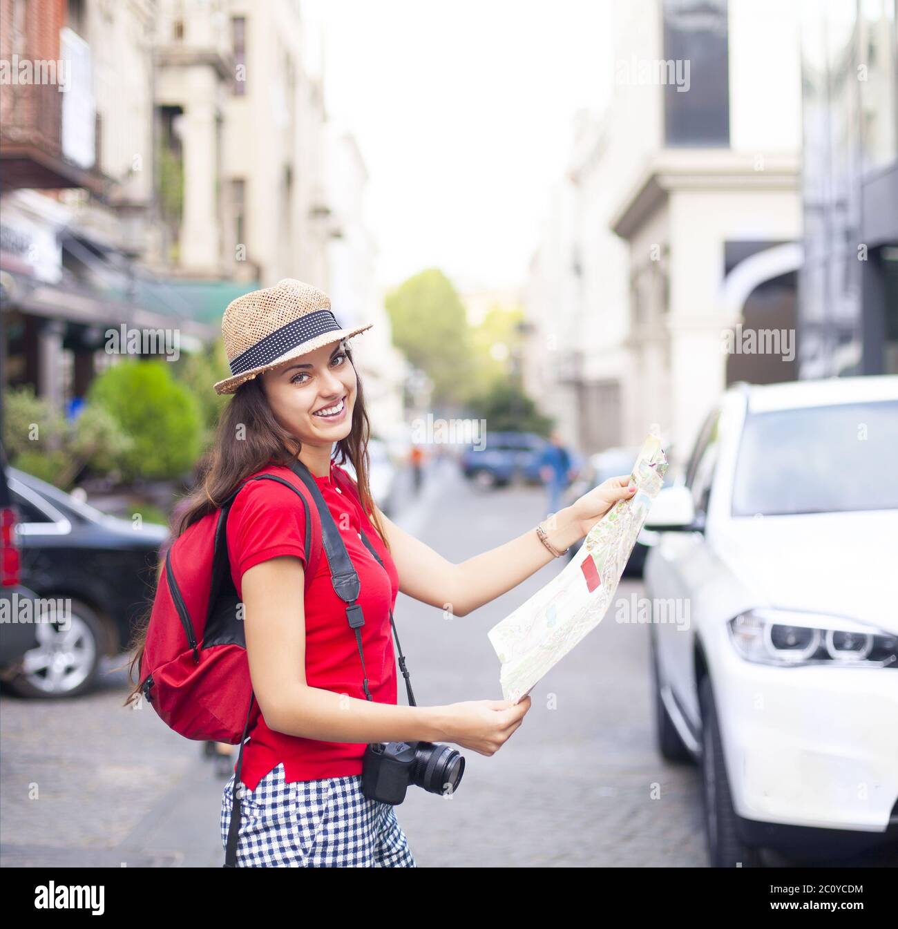 Portrait of a beautiful female tourist searching a place on the map ...