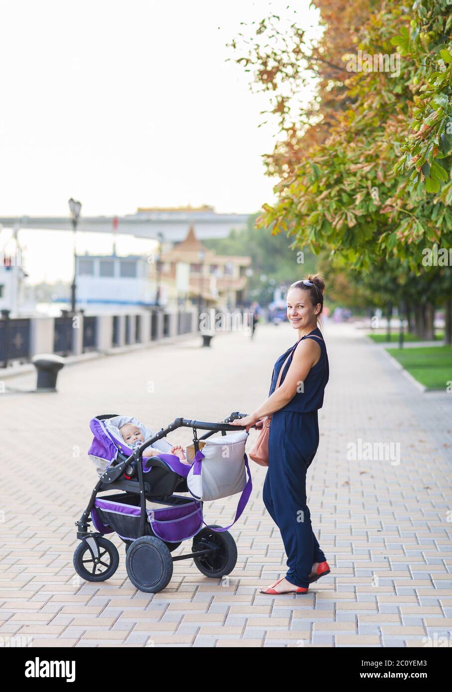 Outdoor portrait of a happy mother and son. Baby sitting in stroller ...