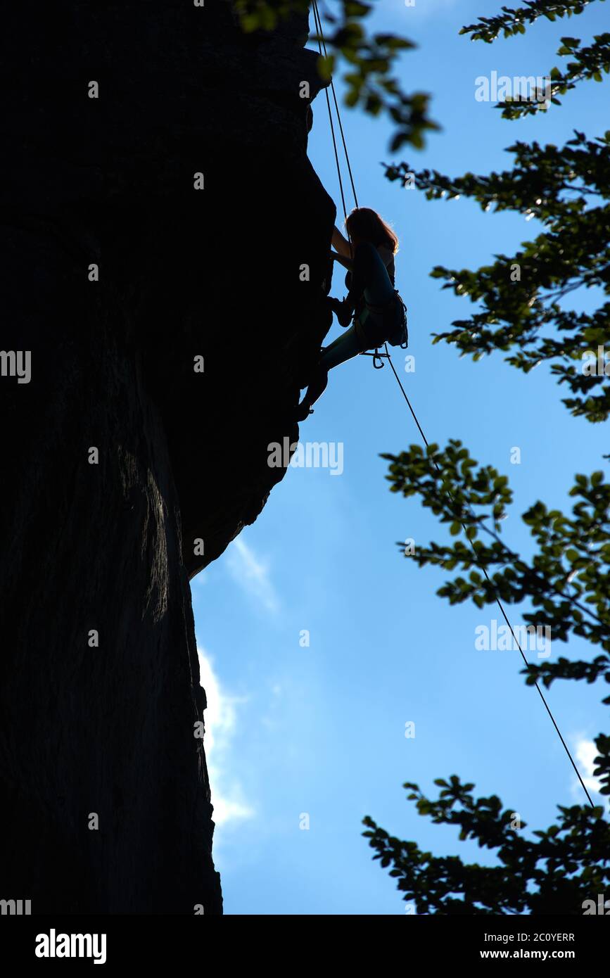 Brave lady mountaineer climbing extremely vertical rock under beautiful ...