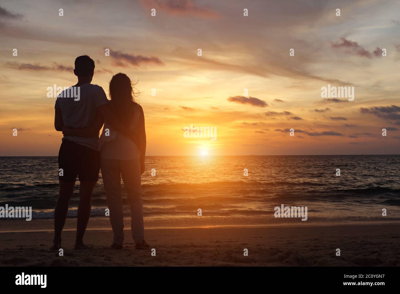 silhouette of young couple hugs on beach at orange sunset backside view ...