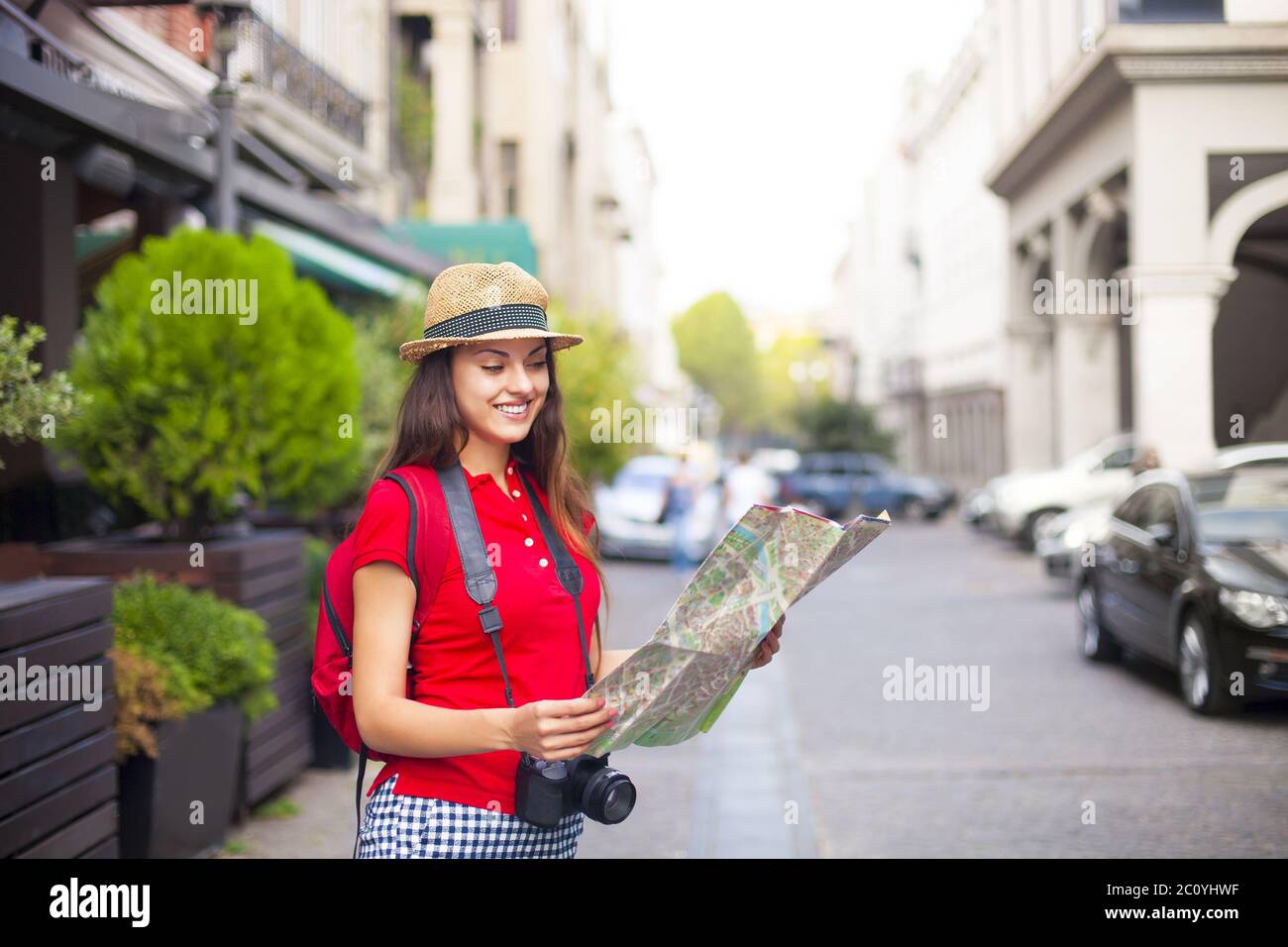 Portrait of a beautiful female tourist searching a place on the map ...