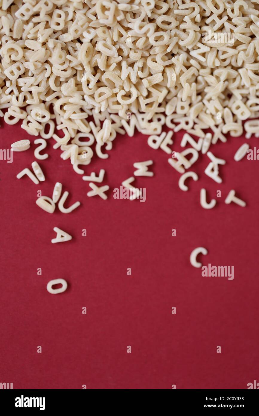 Pasta letters close-up on a bright burgundy background..Dry uncooked ...