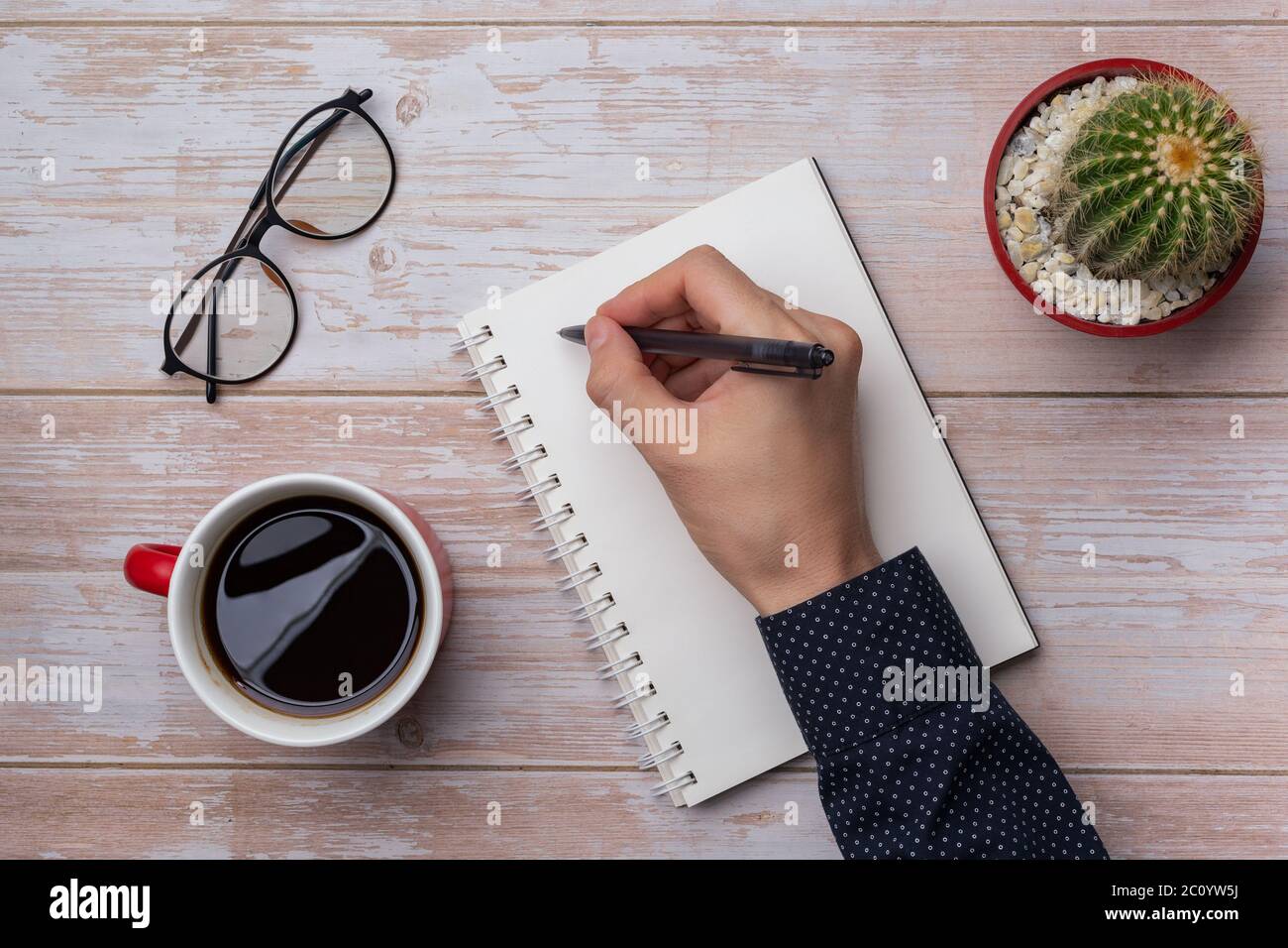 Above view of hand writing taking notes with pen in blank spiral ...