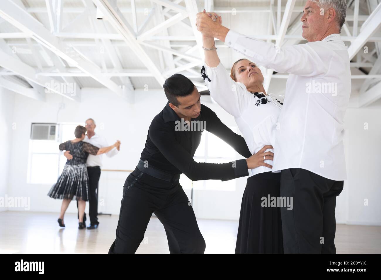 Mixed race dance teacher helping his ballroom dancing class Stock Photo ...
