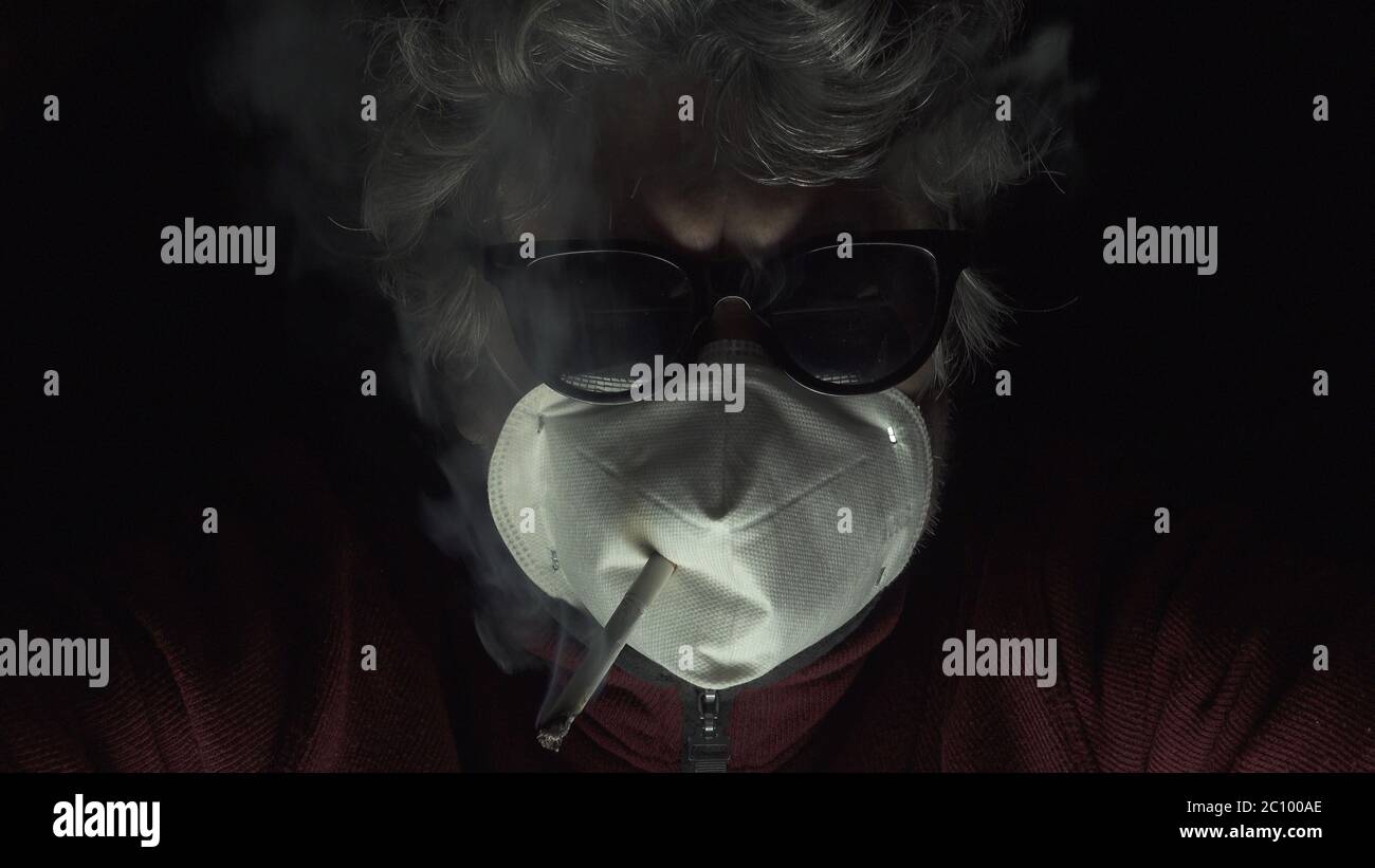 Close up at man wearing sun glasses and medical protection mask smoking ...