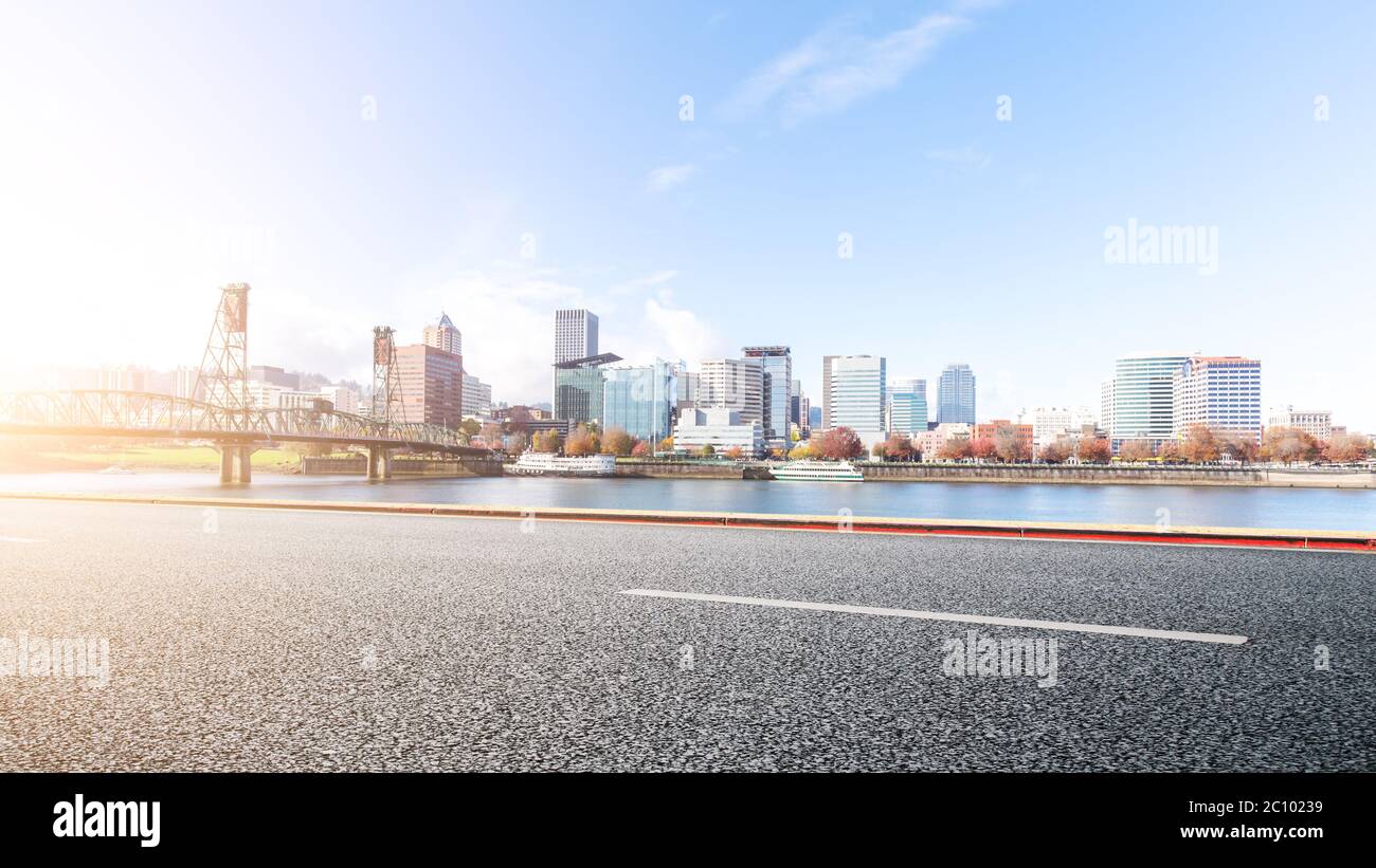 empty asphalt road near water with cityscape and skyline of portland at ...