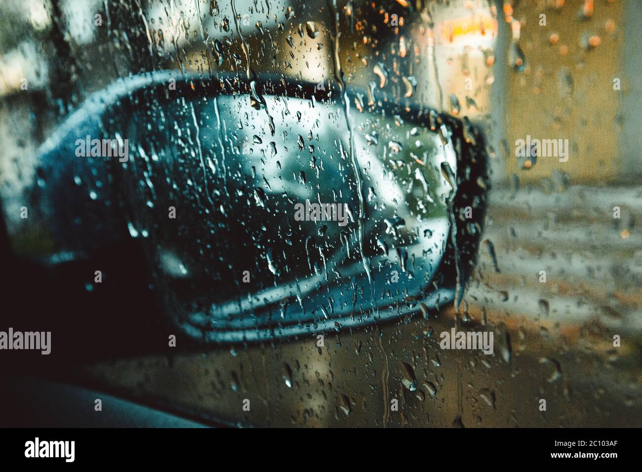 Wet car mirror from the rain through the glass, raindrops close-up ...