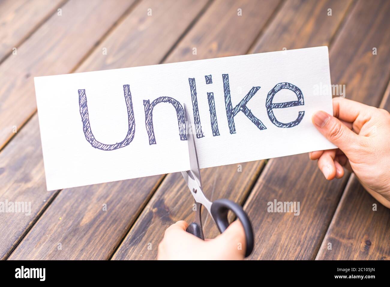 woman holds paper with word unlike by scissors Stock Photo - Alamy