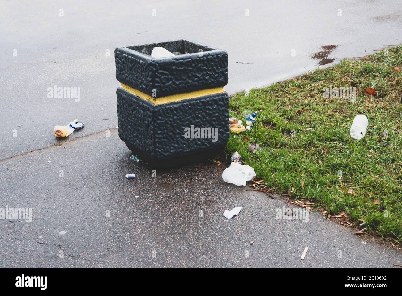 Trash bin and scattered trash on the grass in the park. Garbage ...