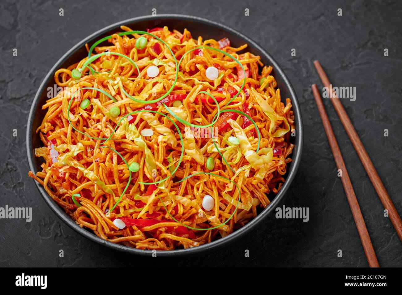 Chinese Bhel in black bowl on dark slate table top. Chinese Bhel is ...