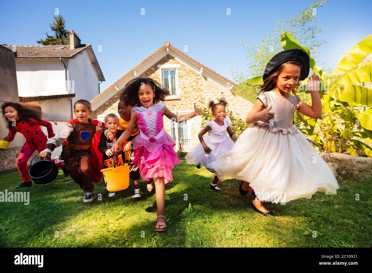 Large group of kids run in Halloween costume on the lawn before the ...