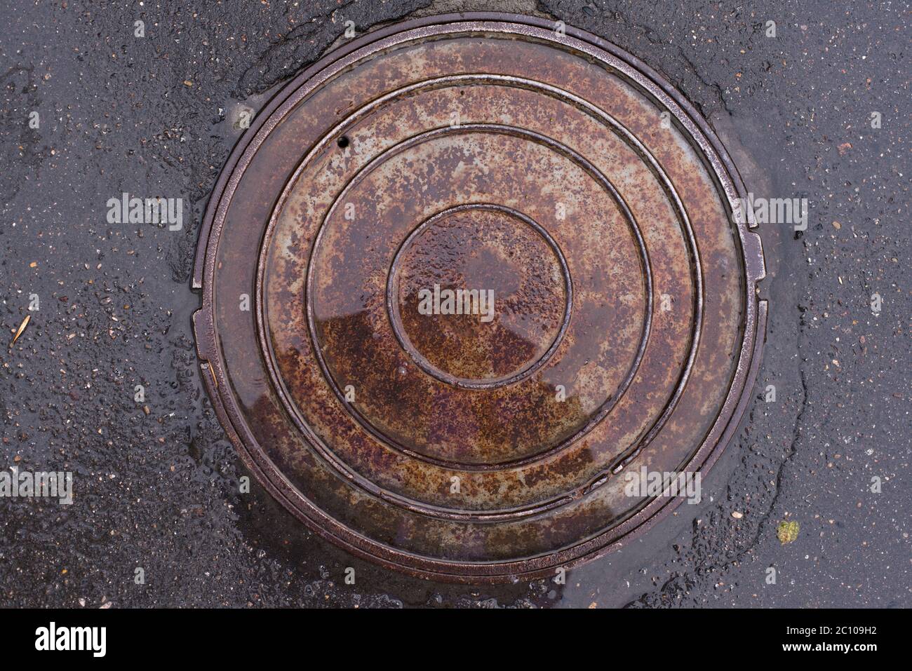 Closeup photo of Old Sewer rust manhole cover on the urban asphalt road ...