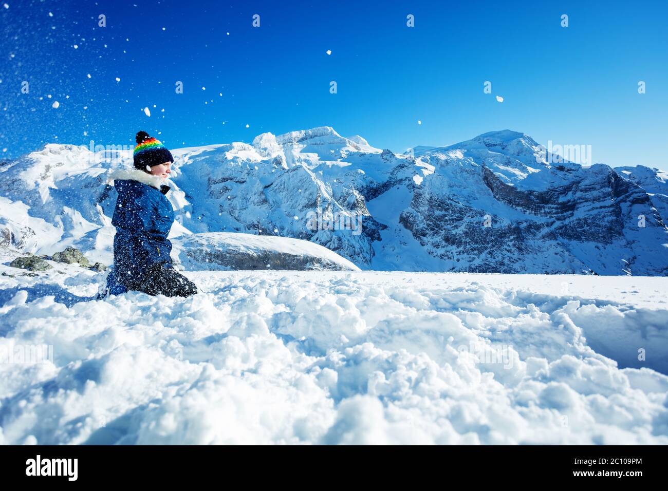 Side portrait of a teenage girl throw snow in the air over mountain ...
