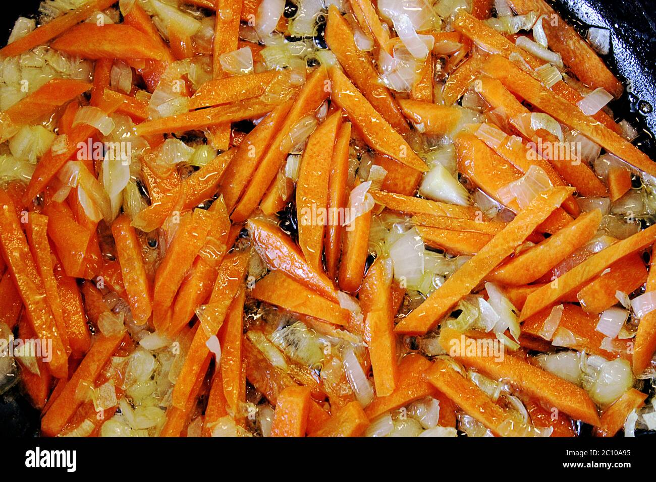 fried onions and carrots in a frying pan in oil Stock Photo - Alamy