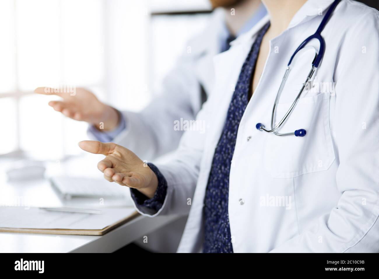 Two doctors sitting and offering helping hand for shaking hand or ...