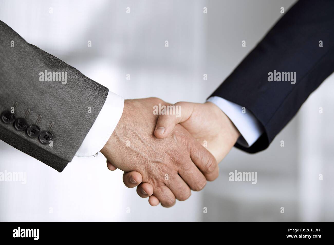 Business people in office suits standing and shaking hands, close-up ...