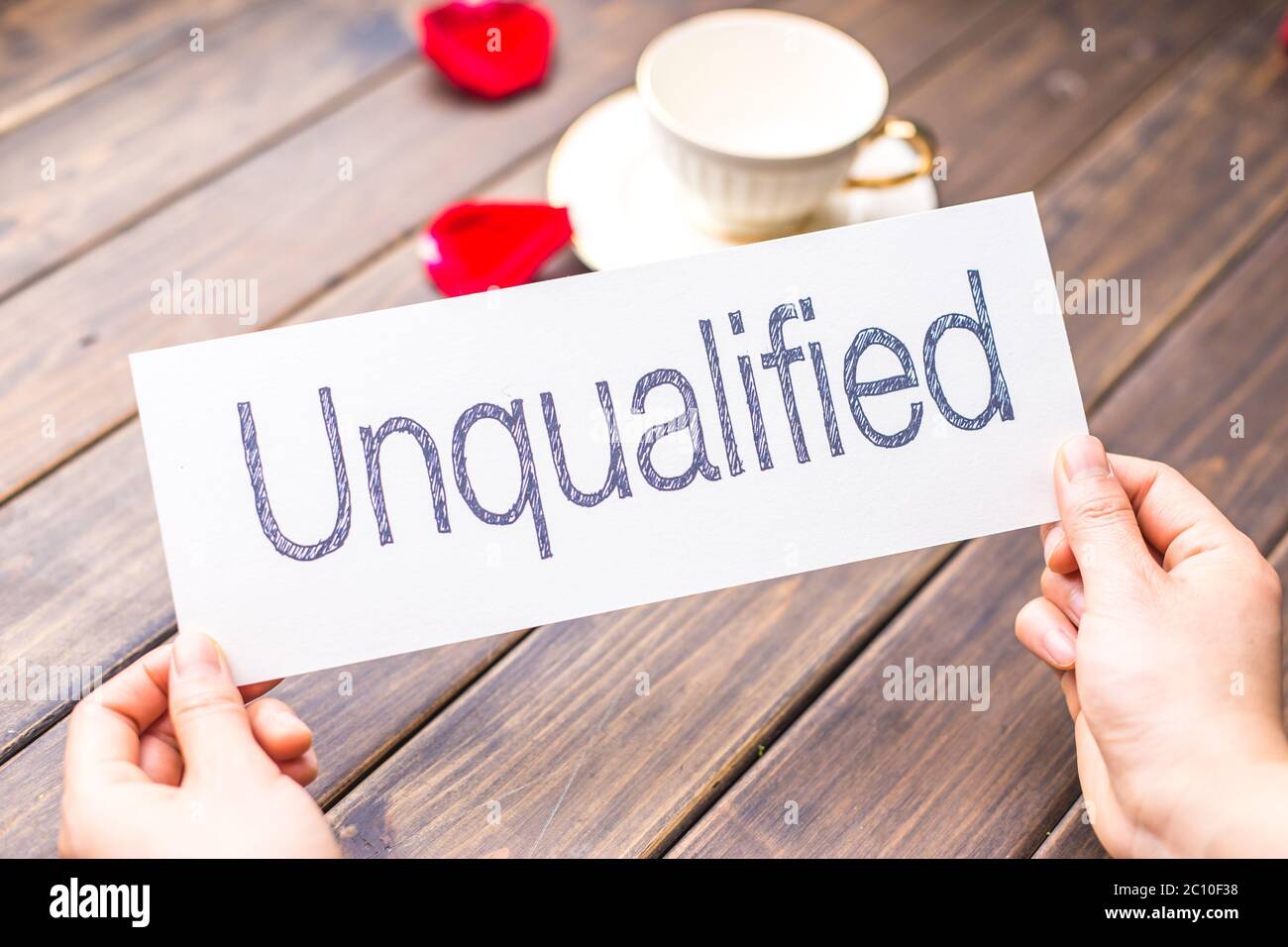 woman holds paper with unqualified in modern cafe Stock Photo - Alamy