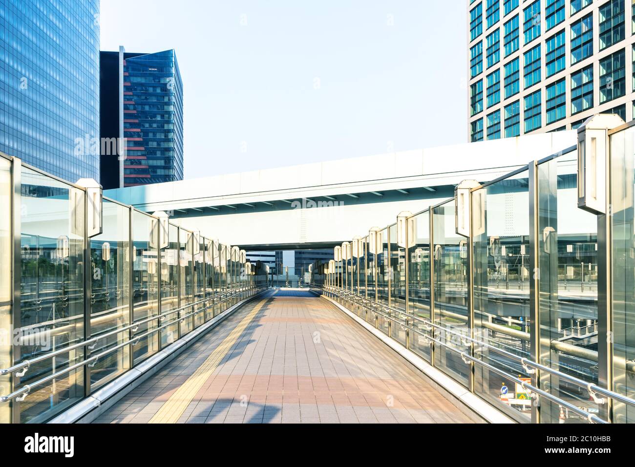 empty footpath through modern office buildings in tokyo with sunbeam ...