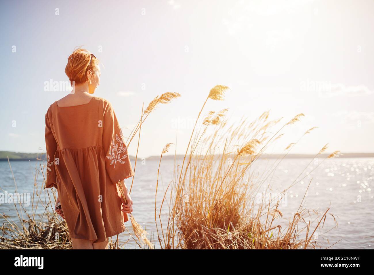 Woman with short hair standing on a lake shore, looking afar Stock ...