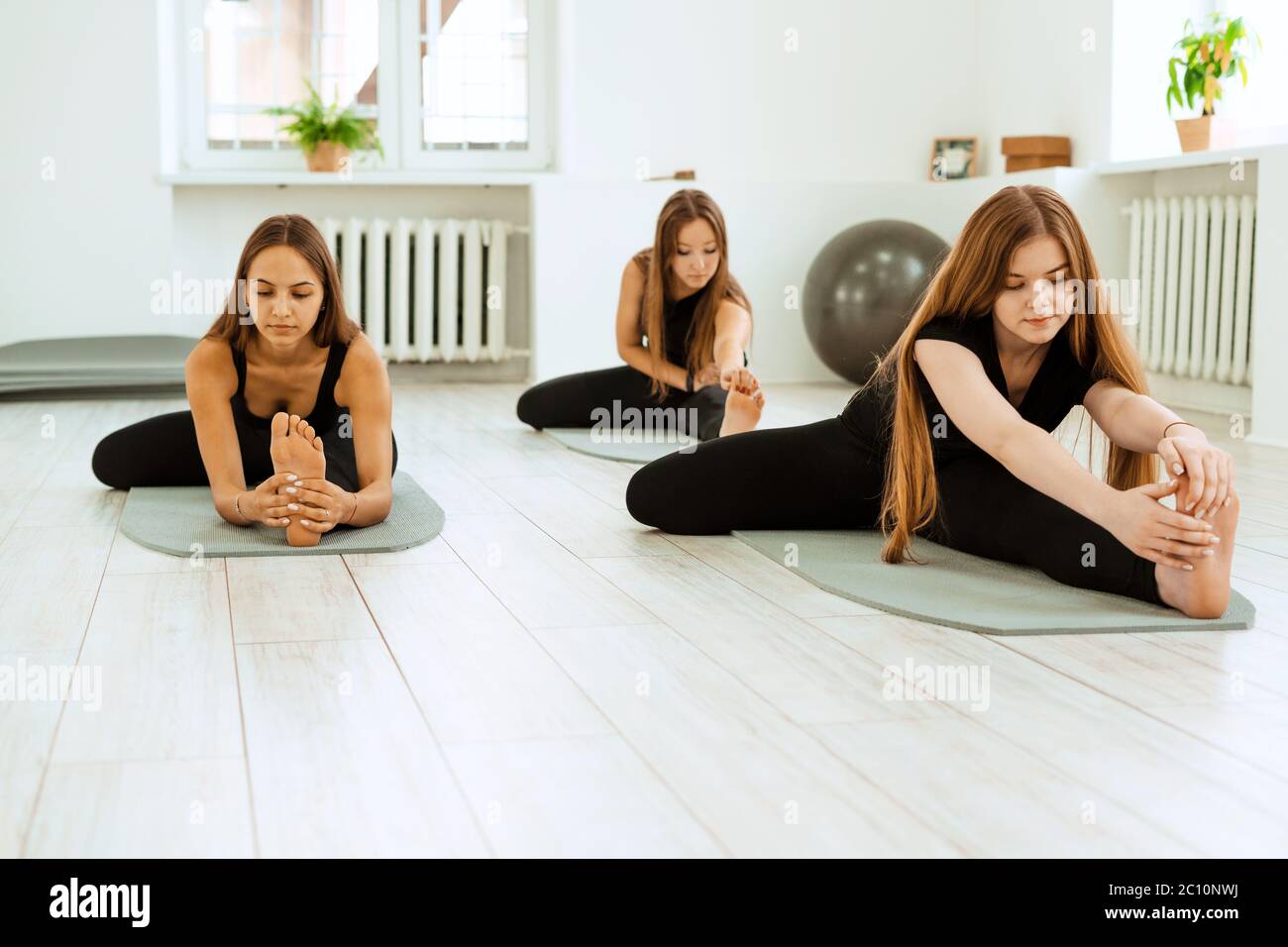 Stretching workout. A group of young girls in black uniforms are doing ...