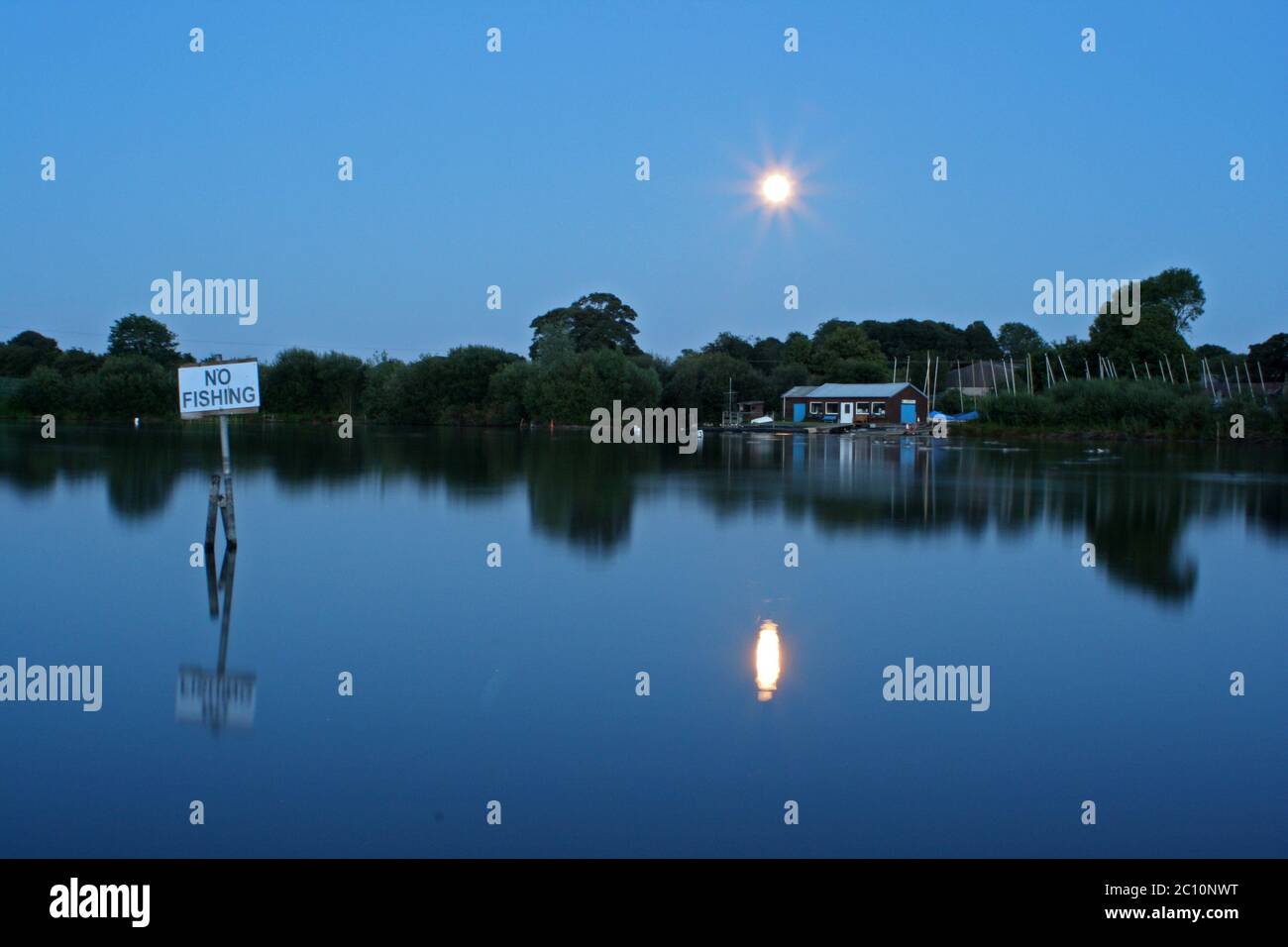 Full moon rising over lake Stock Photo - Alamy