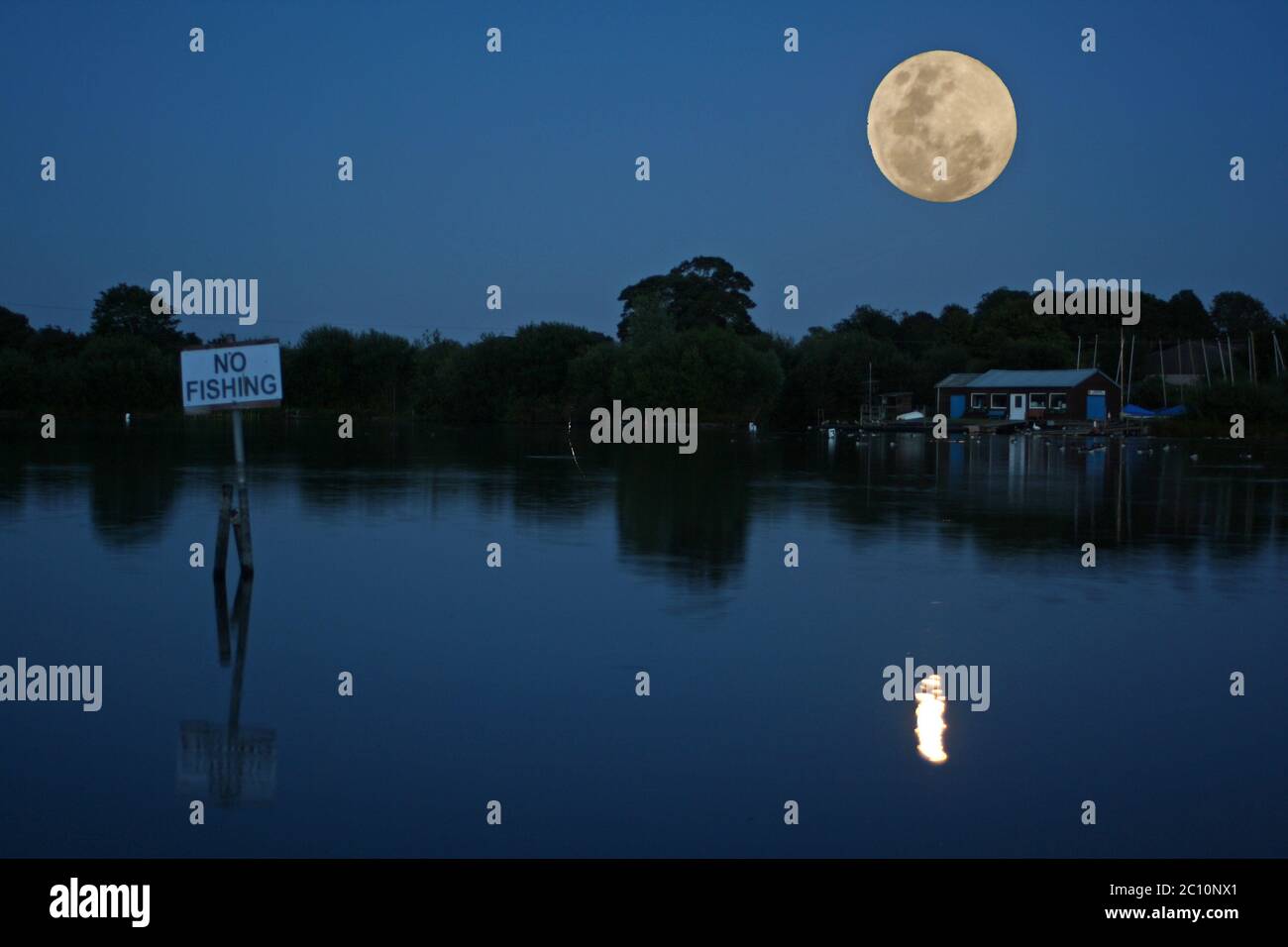Full moon rising over lake Stock Photo - Alamy