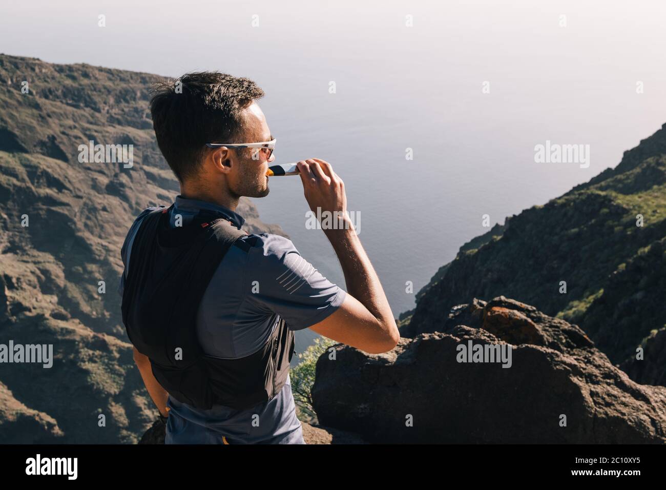 Portrait of young man drinking energy sports nutrition energy gel while ...