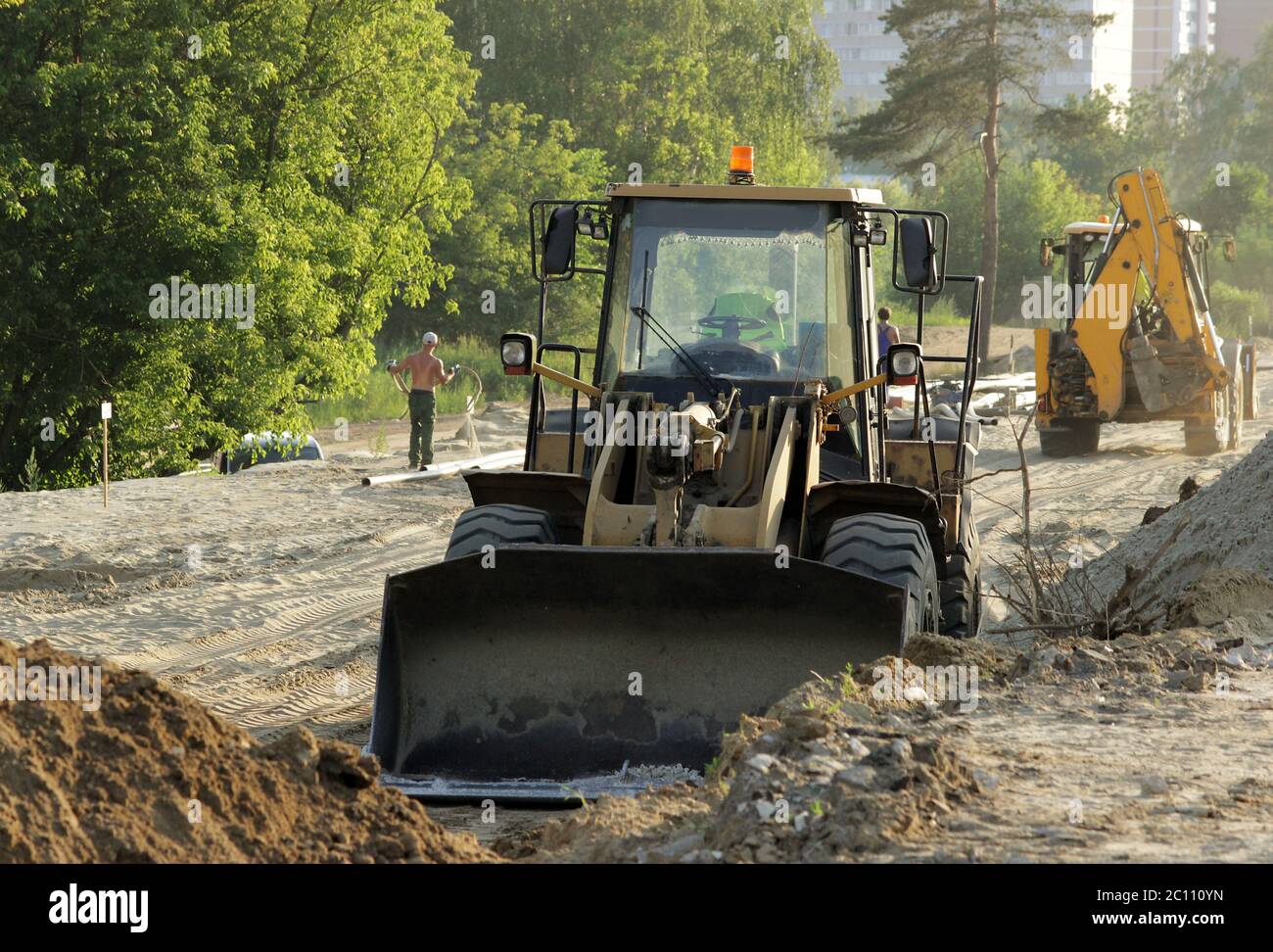 bulldozer, forklift and workers at the construction road junction in ...