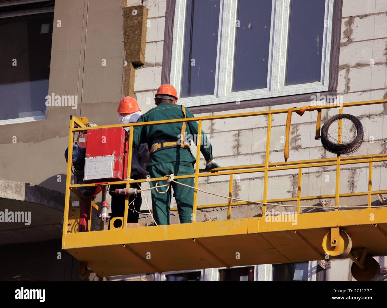 construction suspended yellow cradle with workers on a newly built high ...