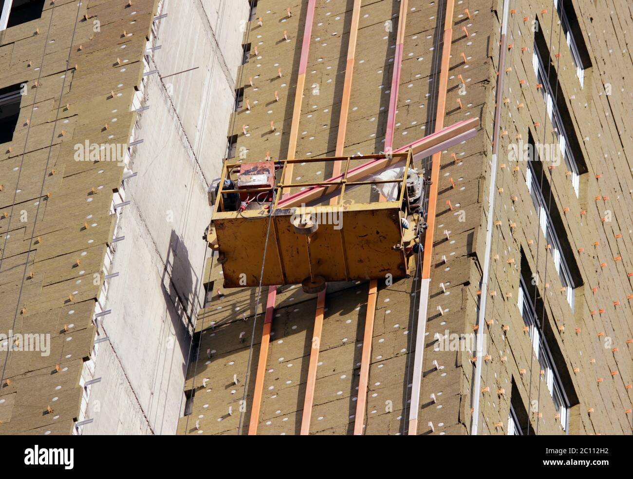 construction suspended yellow cradle with workers on a newly built high ...