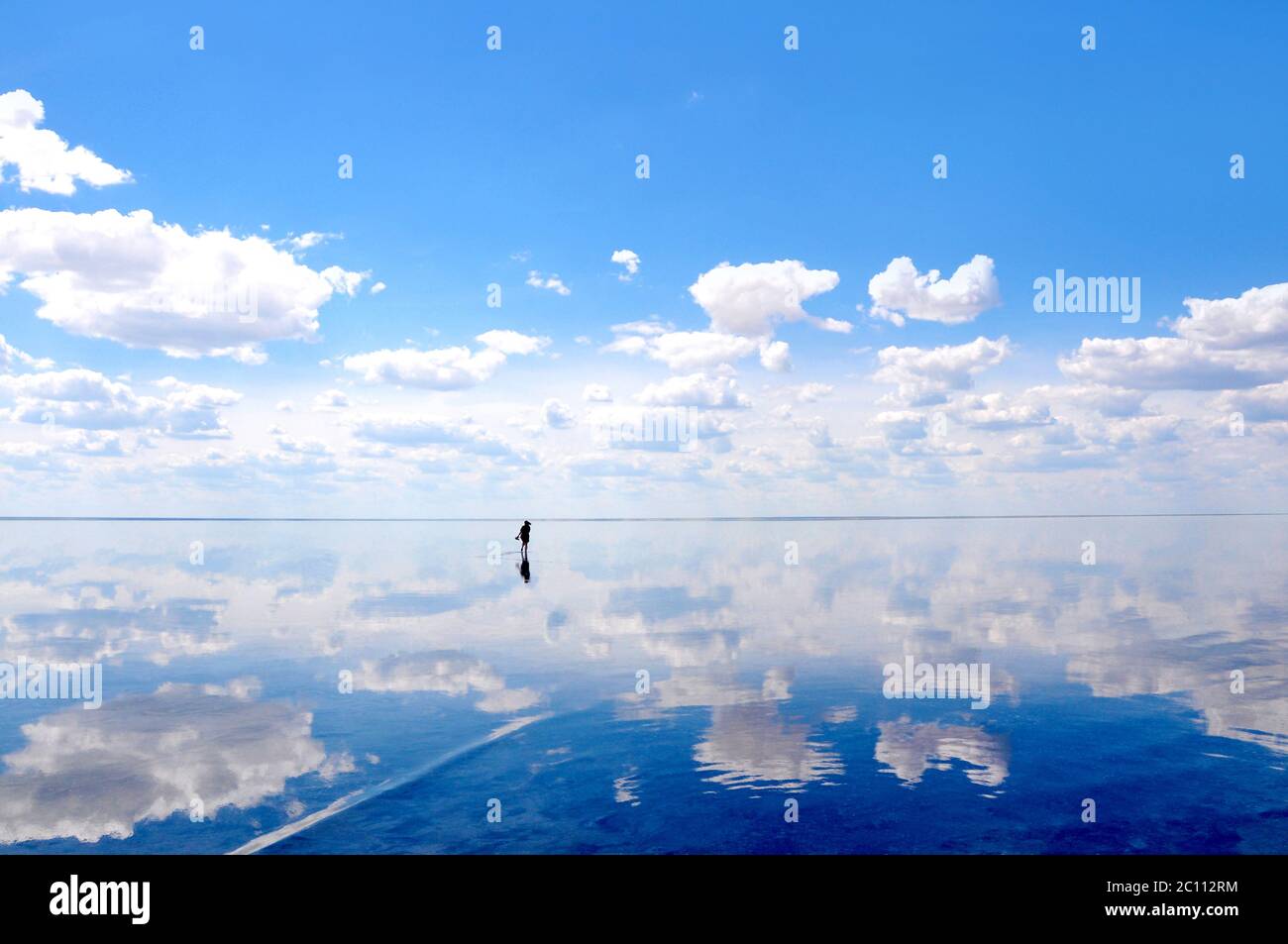 Silhouette walking on the calm water of the lake Elton, the biggest ...