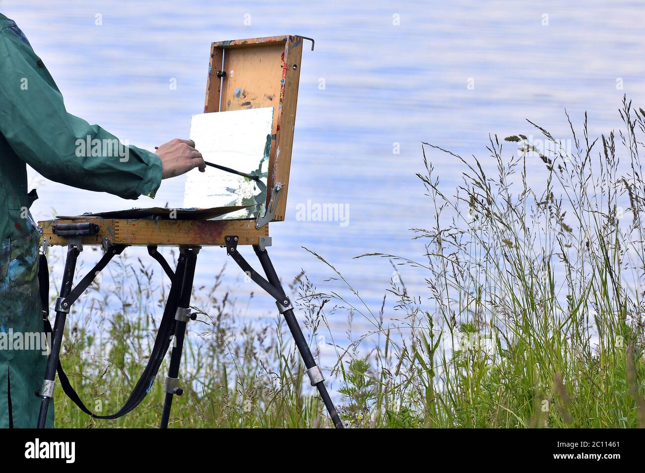 Hands of the artist with a brush, paint a picture on an easel in the ...