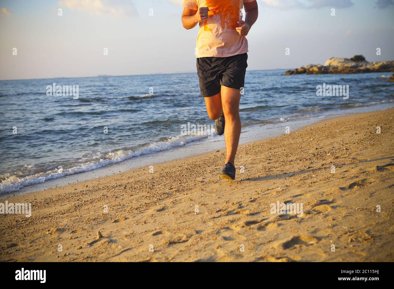 Man running on the beach at sunset Stock Photo - Alamy