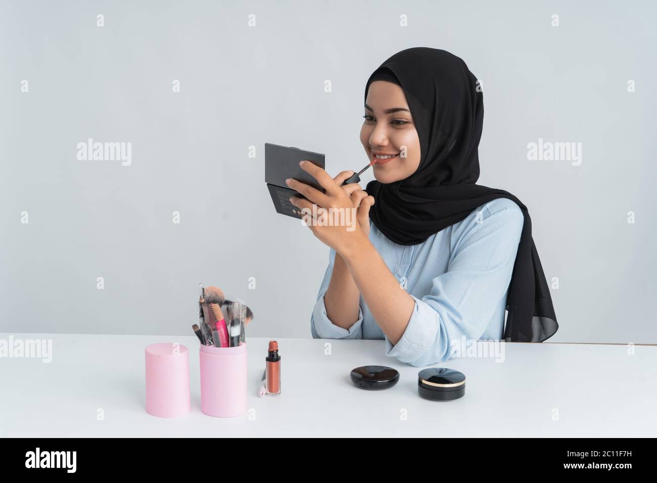 muslim woman applying lip gloss to her lip Stock Photo - Alamy