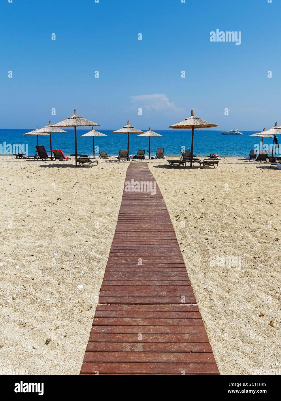 Wooden walkway on a beach in Kefalonia, Greece, leads to sunbeds and ...
