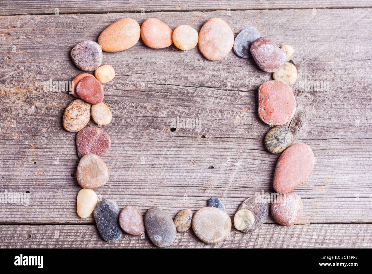small beach stones frame laying on rustic wooden table Stock Photo - Alamy