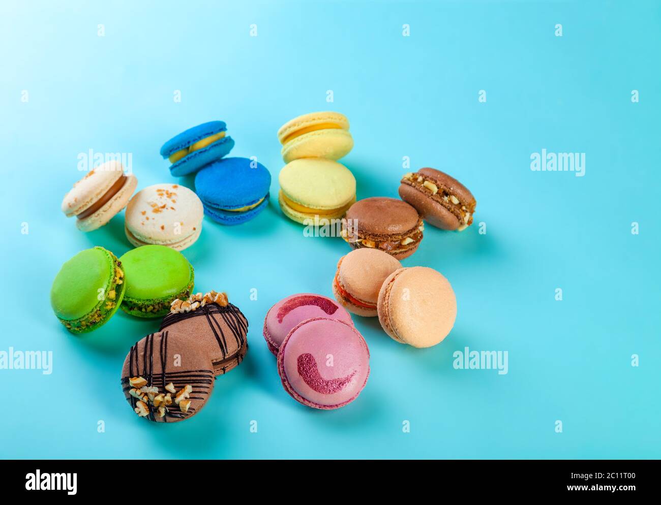 Different types of colorful sweet macaroons dessert on blue background ...