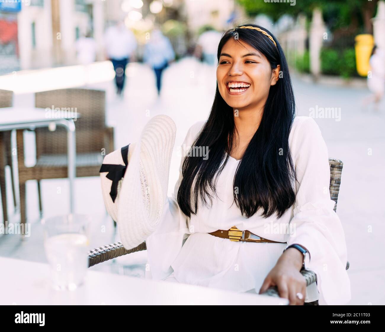 Latin young brunette woman sitting on bar terrace and fanning herself ...