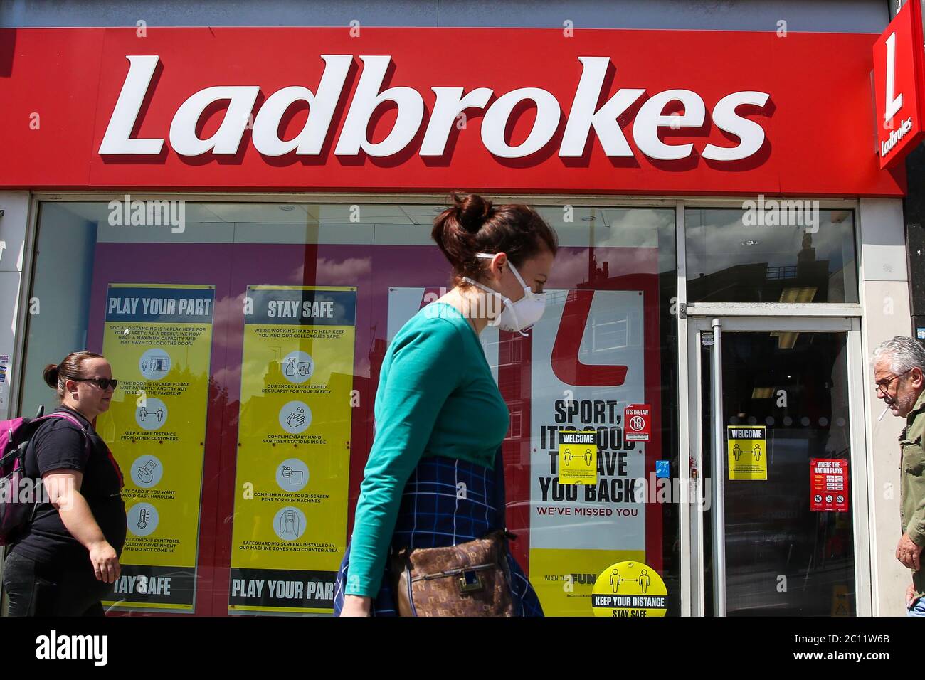 London, UK. 13th June, 2020. A woman wearing a face mask walks past a ...