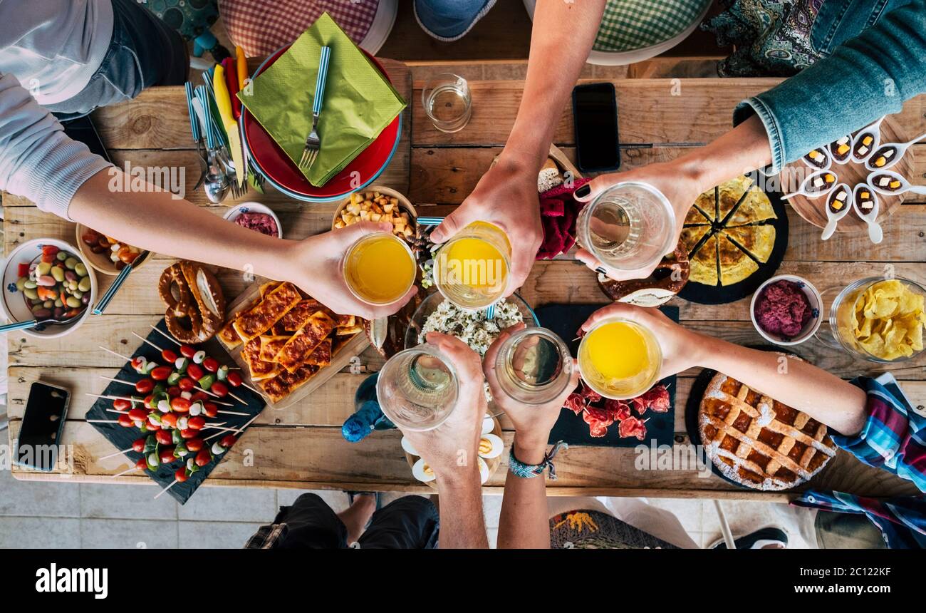 Table with food and friends clinking and toasting together in ...