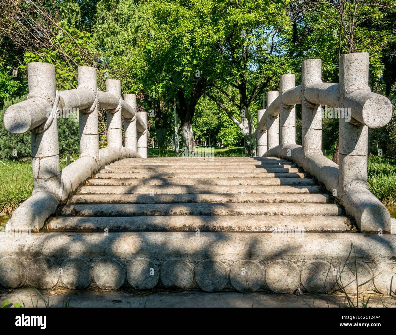A bridge made of stone imitating wood logs. Stone bridge above water ...