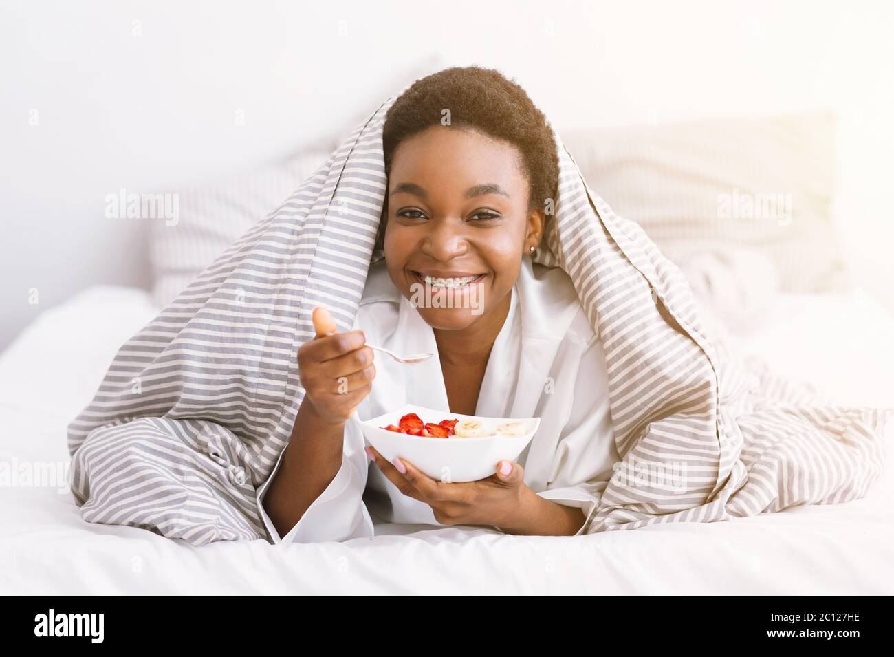 Healthy food. Happy african american girl has breakfast, eating salad ...