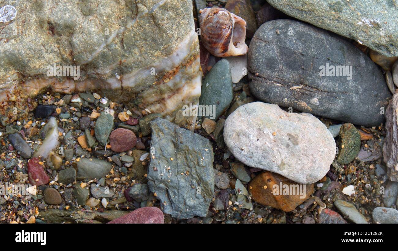 Rocks, pebbles, rock pools, sand and ocean on an overcast June day in ...