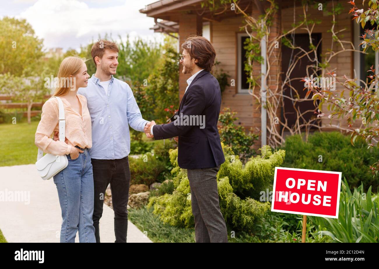 New home owners shaking hands with real estate agent near residential ...