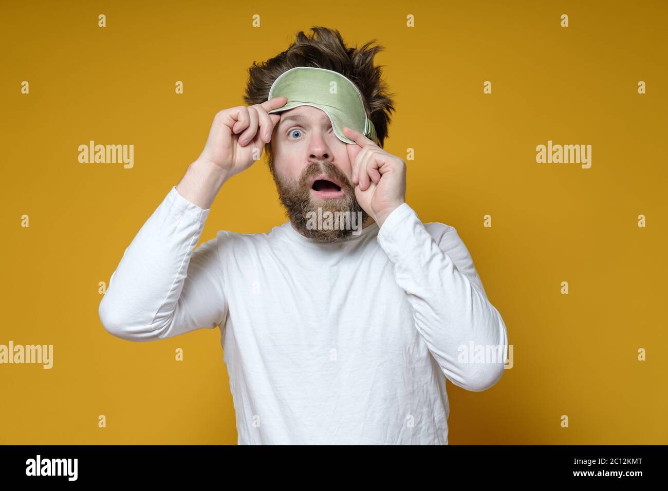 Man with a disheveled hairstyle lifted a sleeping mask from one eye and ...