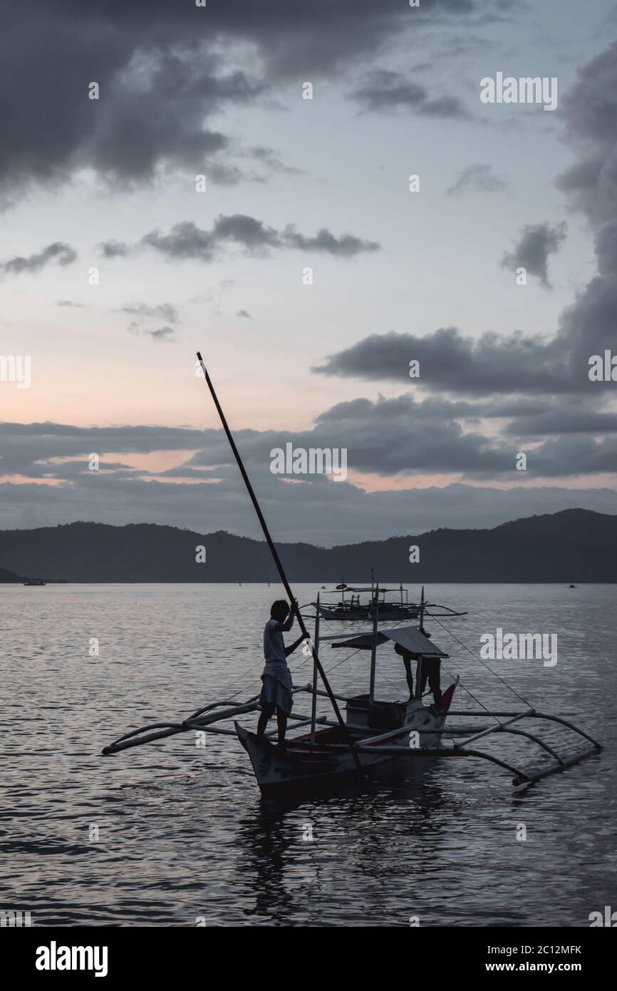 Philippine Fisherman fishing during down on a traditional boat during a ...