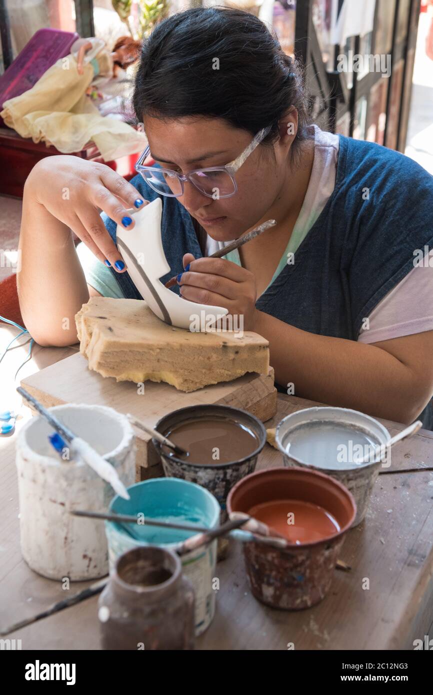 An indigenous Purépecha ceramic artist paints a traditional design on a ...