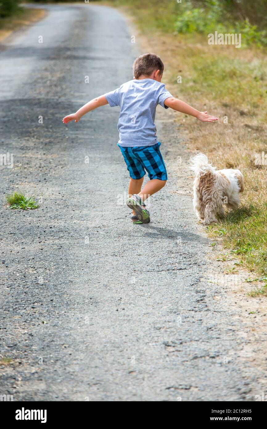 Young child running down the road with small dog Stock Photo - Alamy